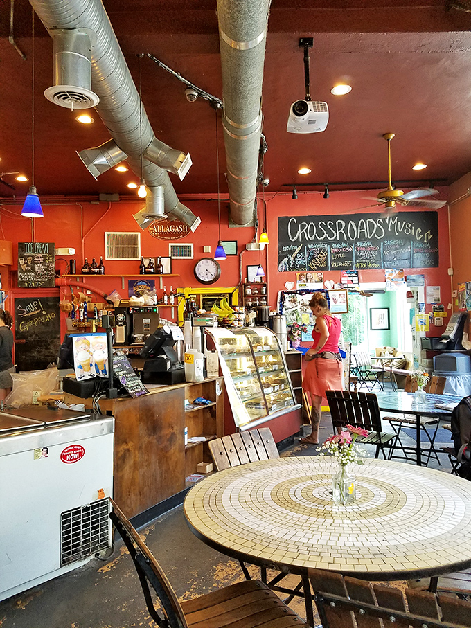 Behind the counter where coffee magic happens&mdash;exposed pipes overhead and pastries below create the perfect backdrop for your morning caffeine transaction.