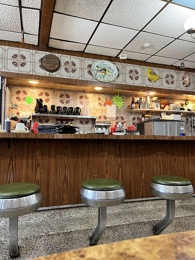 Counter seating where breakfast dreams come true under the watchful eye of vintage decorative plates. Those green stools have supported generations of happy eaters.