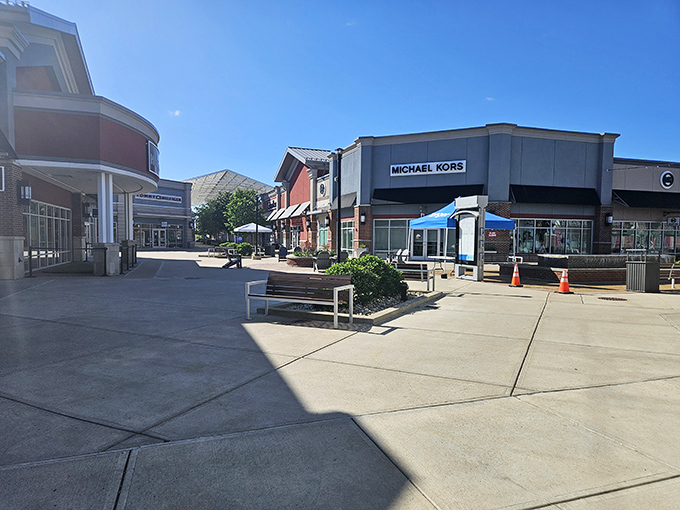 Michael Kors beckons from across the courtyard, promising accessories that say "I'm sophisticated" without whispering "I'm broke." The benches are perfectly positioned for partners waiting patiently.
