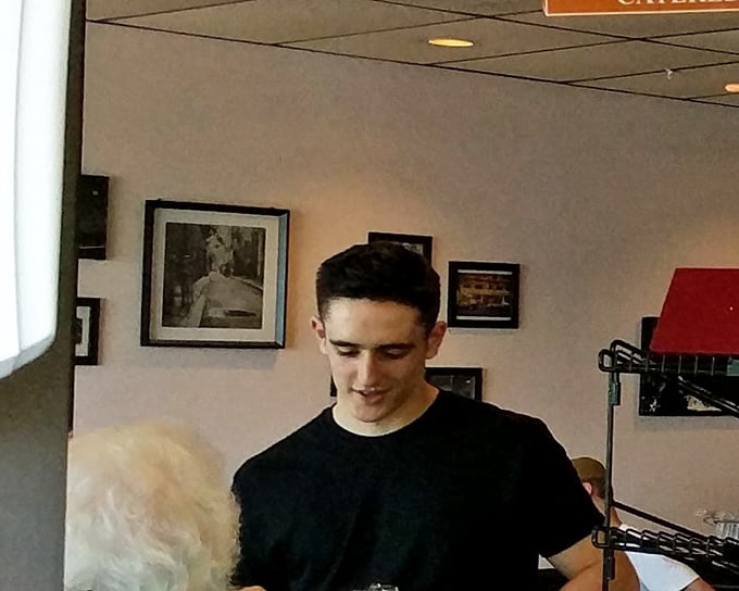 Behind the counter, culinary choreography unfolds as another satisfied customer's order comes to life.