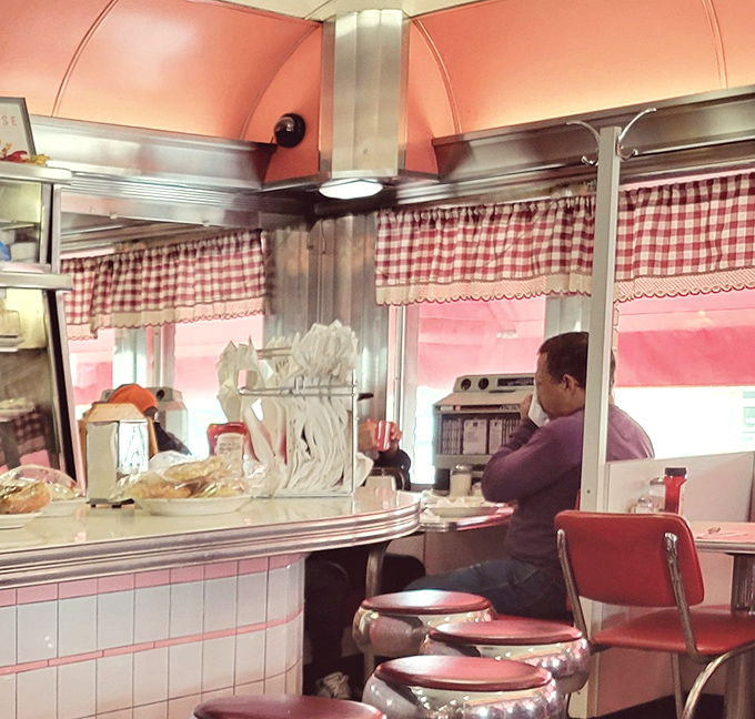 Red and white checkered curtains frame the classic diner counter, where desserts under glass domes tempt even the most determined dieters.