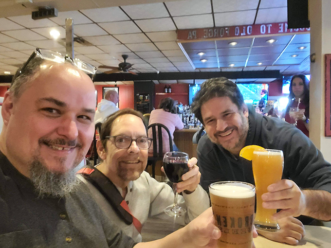 Three friends raising glasses in a toast that says, "We came for the pizza but stayed for the camaraderie"&mdash;the universal language of good times.