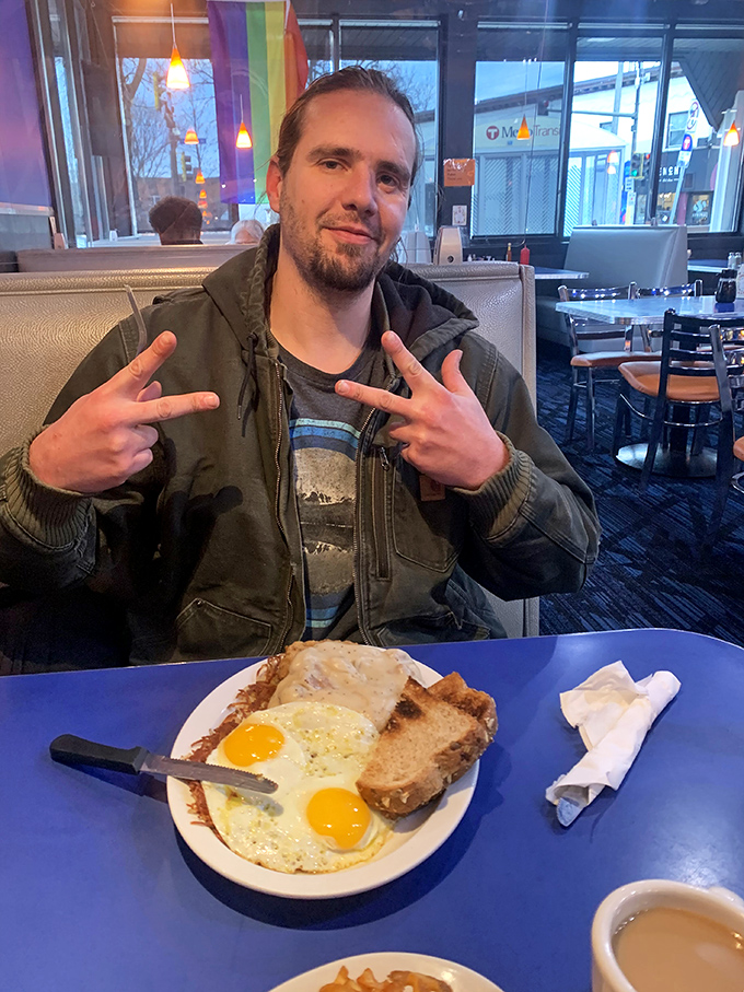 A satisfied customer gives the universal sign of breakfast approval. Those sunny-side-up eggs are practically winking back at him.