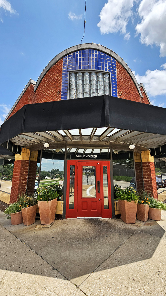 The welcoming entrance, framed by terracotta planters and that distinctive curved facade, promises comfort before you even step inside.