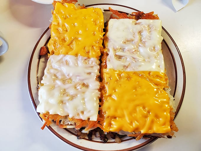 Hashbrowns wearing their cheese proudly&mdash;a patchwork quilt of yellow and white dairy goodness atop crispy potatoes. Breakfast architecture at its finest.