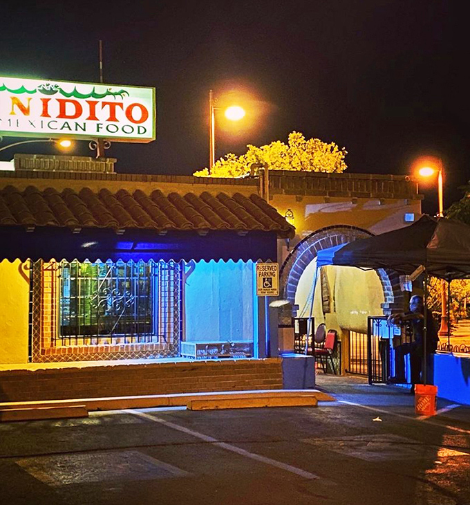 As night falls, Mi Nidito glows like a beacon of culinary promise. The blue-lit entrance arch invites you into a world where calories don't count after dark.