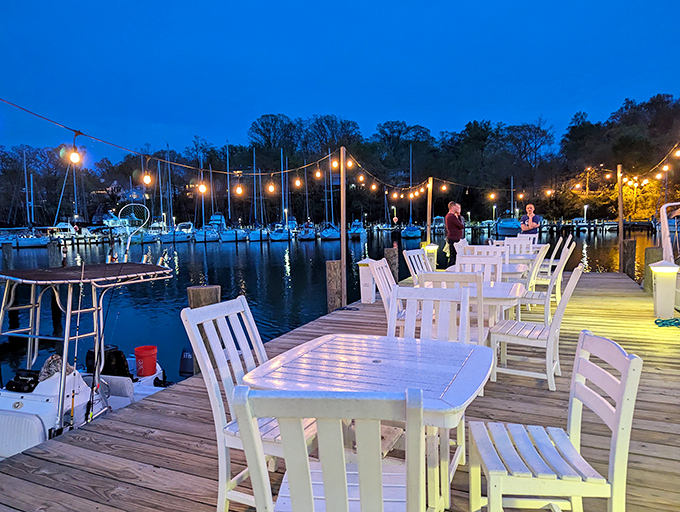 Evening outdoor dining on the dock with string lights and sailboats creates memories worth more than photographs capture.