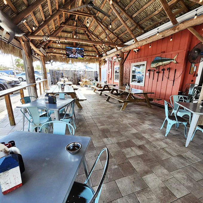 The thatched roof palapa and string lights transform simple outdoor seating into waterfront dining paradise perfection.
