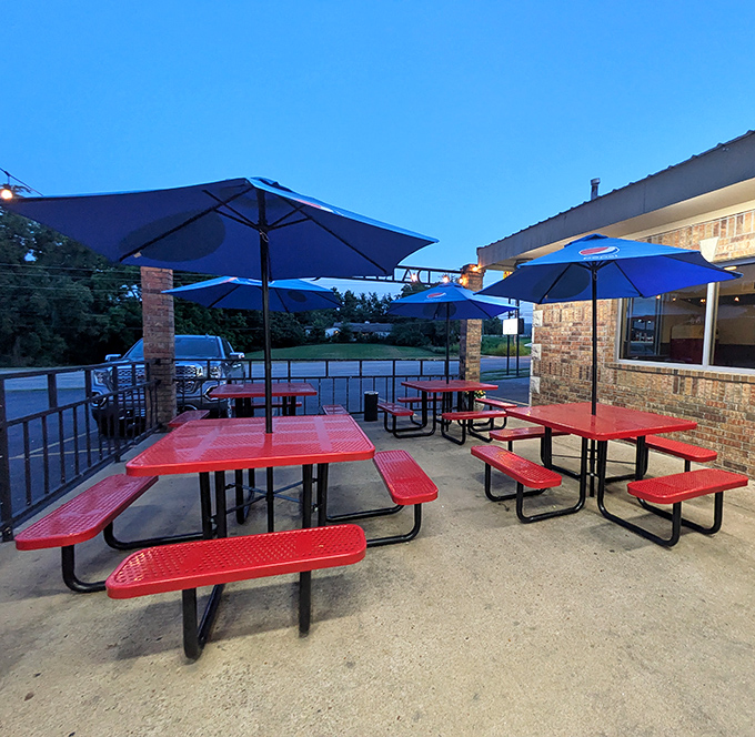 Outdoor picnic tables under blue umbrellas, perfect for enjoying Arkansas evenings with your shake and fries.