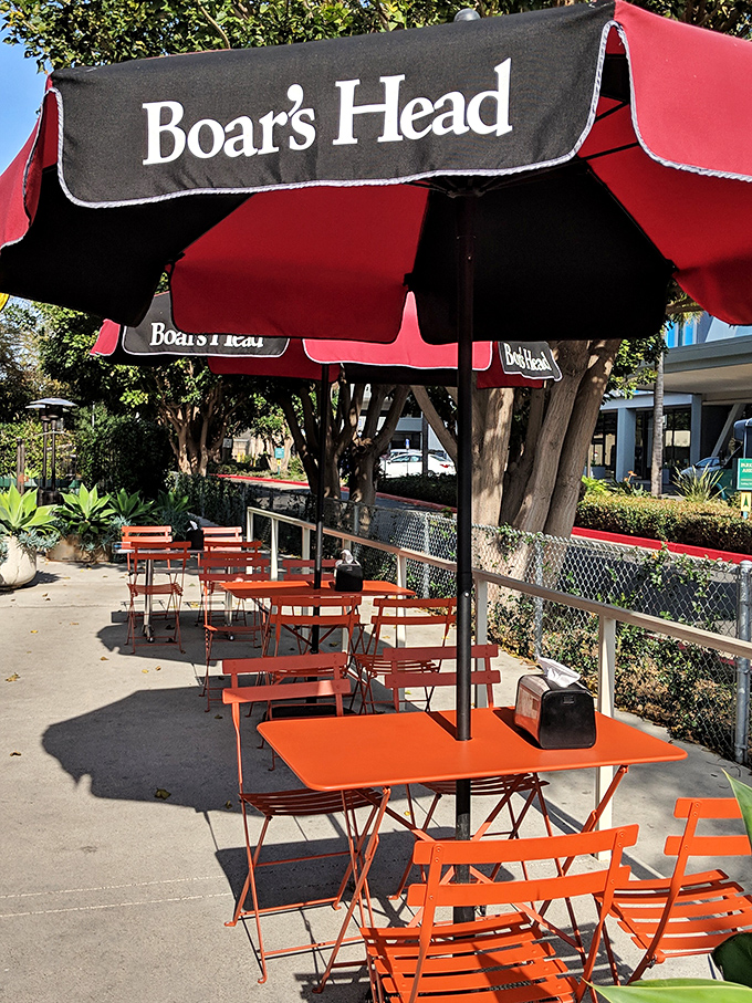 The outdoor seating area under Boar's Head umbrellas&mdash;where Los Angeles sunshine meets sandwich perfection in urban harmony.