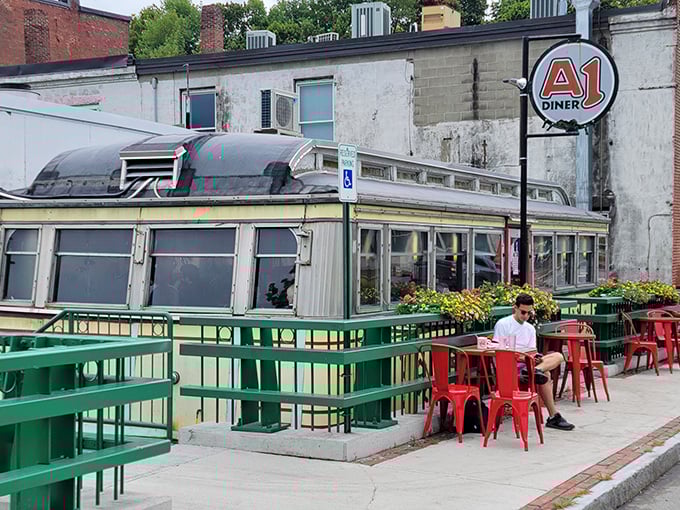 Outdoor seating adds a modern touch to this vintage diner, where red metal chairs pop against the classic silver exterior.