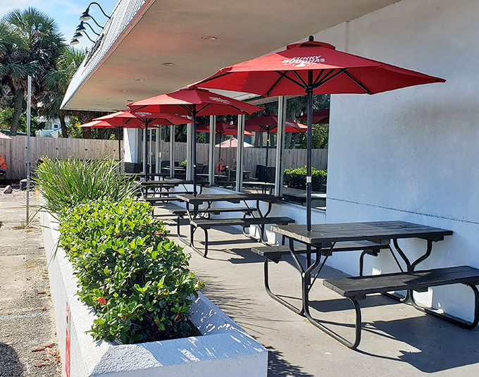 Red umbrellas stand guard over outdoor tables like cheerful sentinels, offering shade and style in equal measure.
