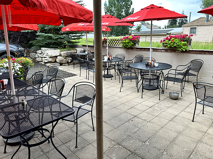 Summer dining under red umbrellas, where mountain breezes complement your meal and flower boxes add splashes of color to your outdoor feast.