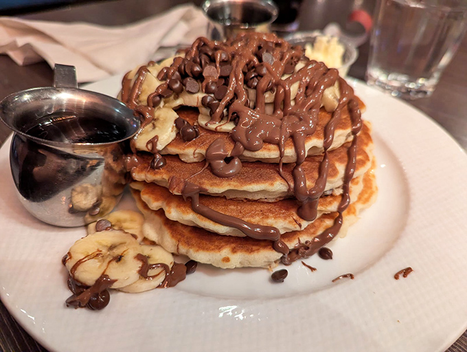 Chocolate chip banana pancakes stacked higher than your weekend expectations, drizzled with a chocolate sauce river of pure joy.
