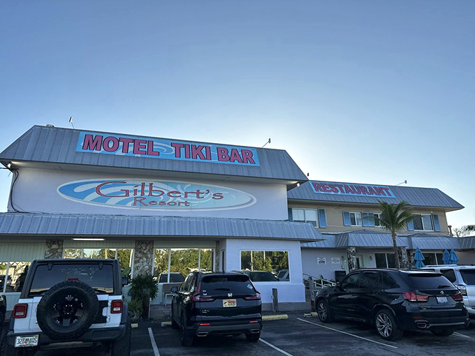 The parking lot view that signals you've arrived. That "MOTEL-TIKI BAR" sign might as well say "Your real life is now on pause."