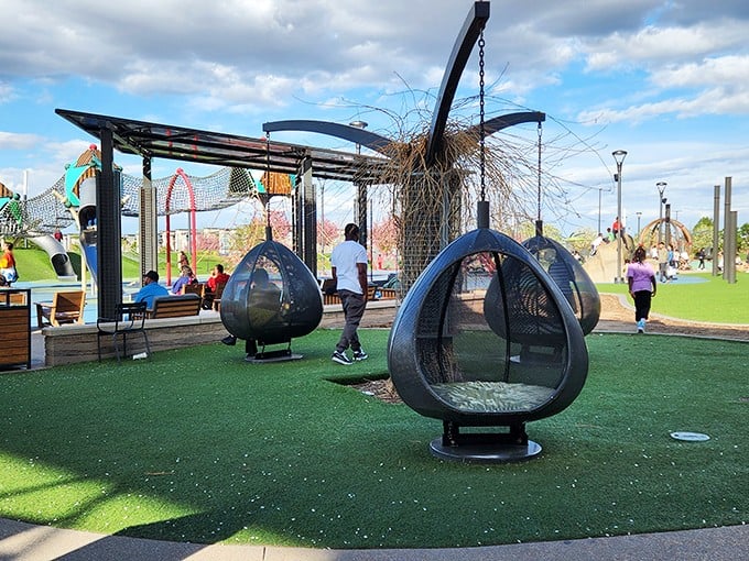 The playground's futuristic pod swings keep kids entertained while parents debate whether they really need another pair of discounted sunglasses.