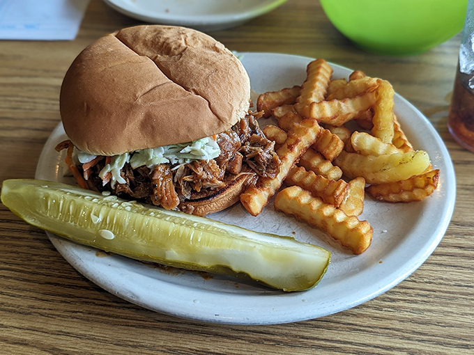 A pulled pork sandwich with crispy crinkle-cut fries and a pickle spear&mdash;simple pleasures that remind you why classics never go out of style.