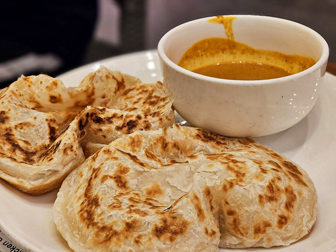 Roti canai: Where flatbread achieves such perfect flakiness that croissants text it for advice, served with curry that demands to be scooped up.