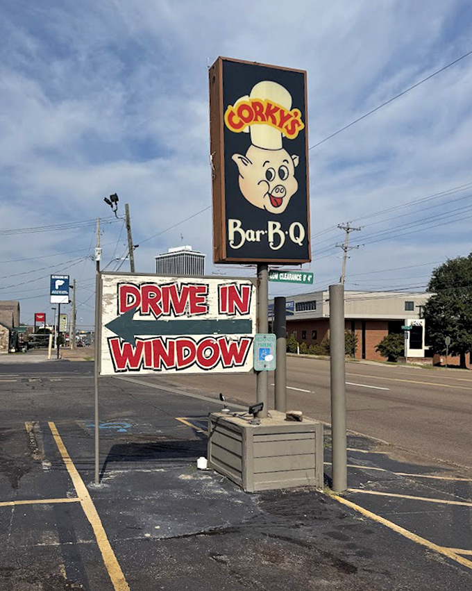 The roadside sign stands like a barbecue lighthouse, guiding hungry travelers to the promised land of pulled pork and ribs.
