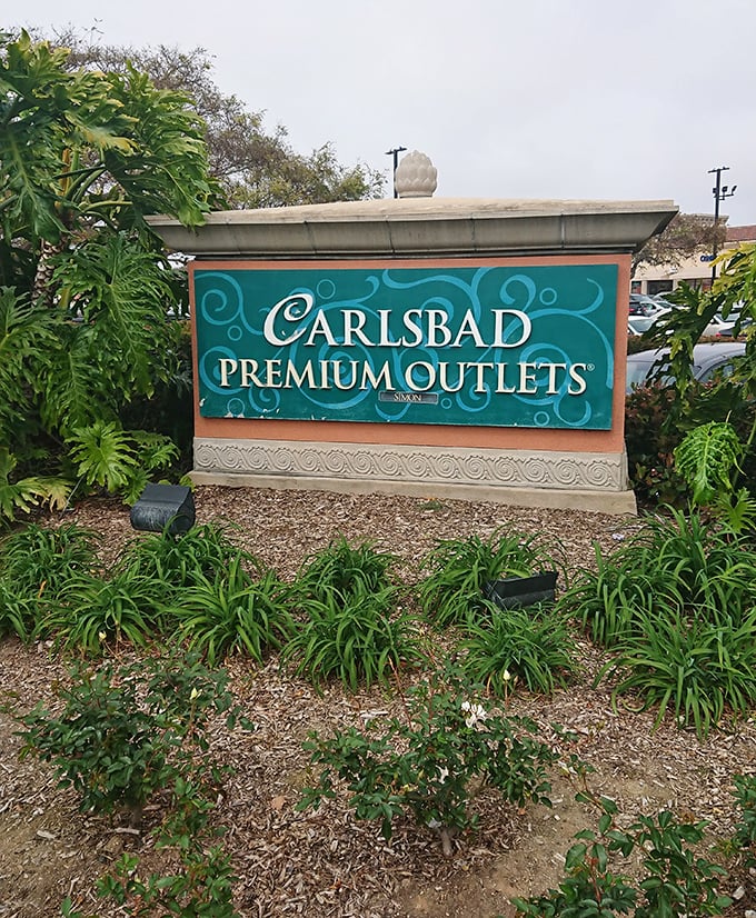 The official welcome sign, surrounded by lush landscaping, promises premium experiences without the premium prices&mdash;California's version of retail paradise.