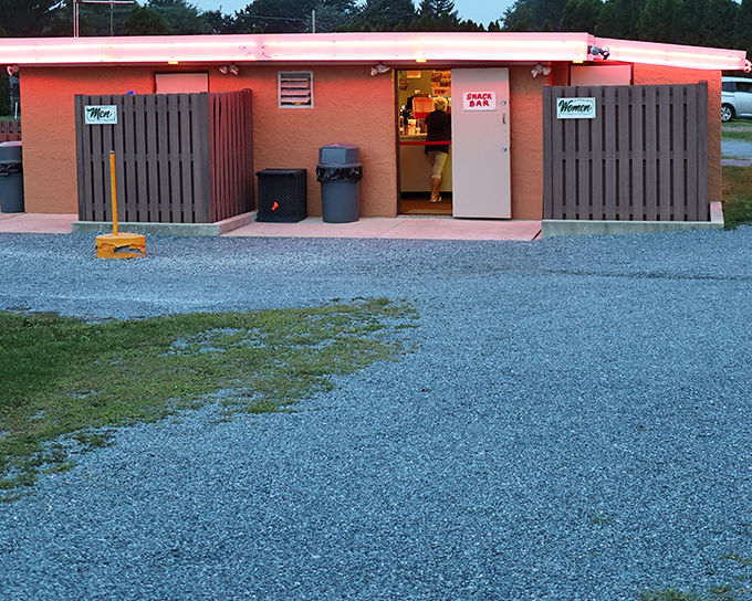 The snack bar's pink glow signals intermission treats &ndash; the essential companion to any proper drive-in experience.