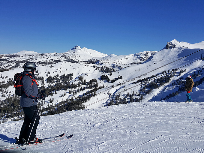 Skiers pausing to absorb panoramic Sierra views. That moment when you realize why people willingly strap slippery boards to their feet.