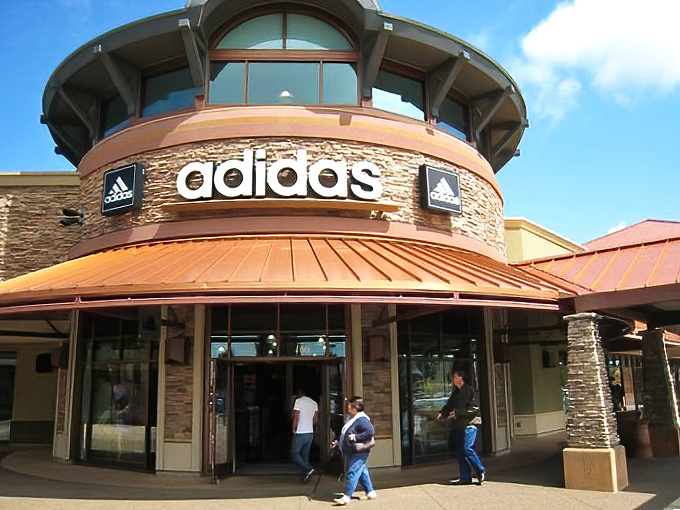 The distinctive Adidas storefront stands like a temple to sportswear. Three stripes, countless options, one very happy credit card.