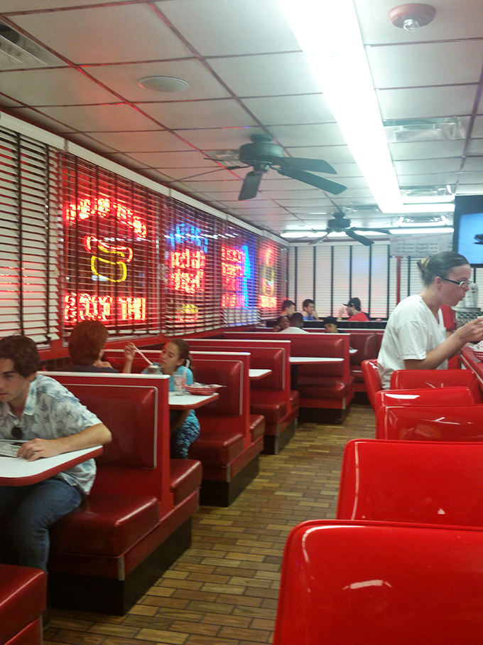 The glow of vintage neon signs bathes those red booths in a warm light that makes everyone look like they're starring in their own retro sitcom.