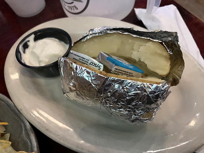 The humble baked potato, wrapped in foil like a present waiting to be unwrapped, proves that sometimes the simplest pleasures deliver the most satisfaction.