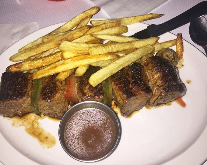 The Beef Brochette arrives like a savory still life&mdash;meat, peppers, and fries arranged in a composition that's both art and dinner.