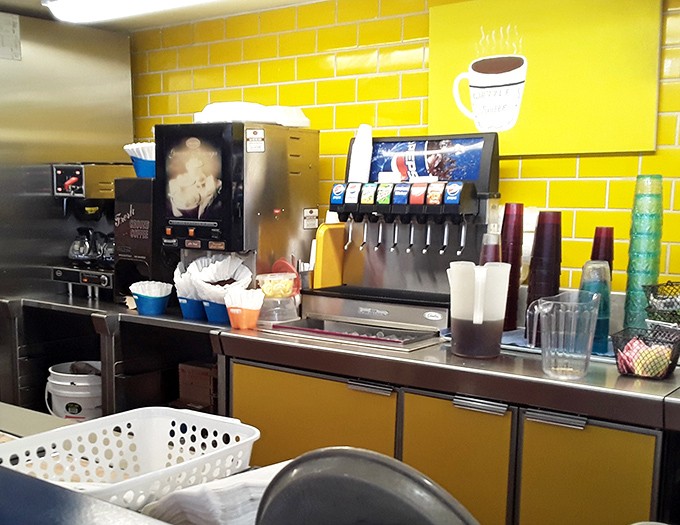 The beverage station stands ready with a cheerful yellow backdrop, because coffee and orange juice deserve proper presentation too.