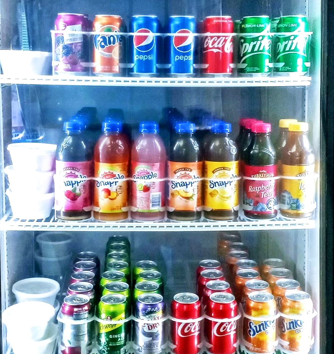 The beverage cooler stands ready with colorful soldiers of refreshment, perfect companions for the flavor explosion happening on your plate.