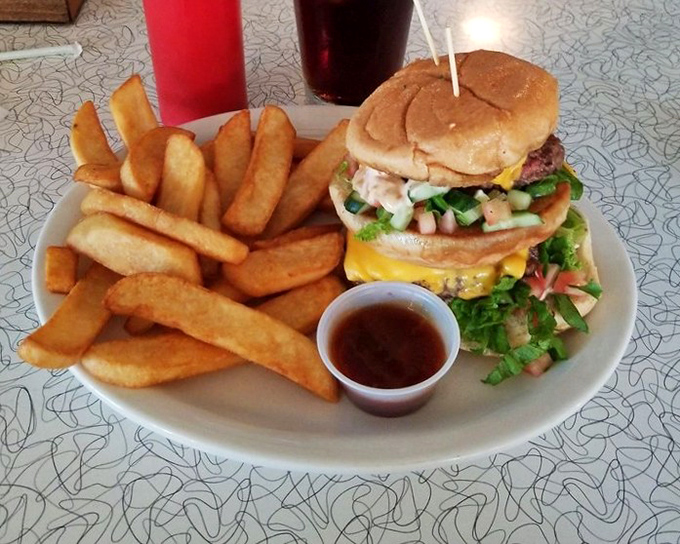 A burger piled high with fresh toppings and paired with golden fries – the kind of honest, unpretentious plate that makes you wonder why anyone bothers with fancy food.