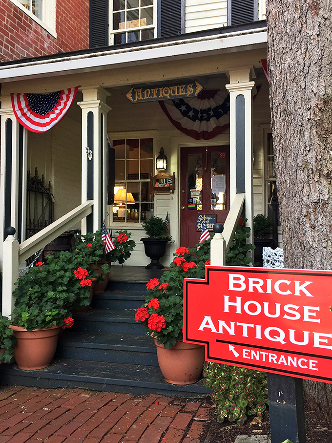 Brick House Antiques welcomes visitors with quintessential small-town charm—red geraniums, American flags, and the promise of discoveries waiting inside.