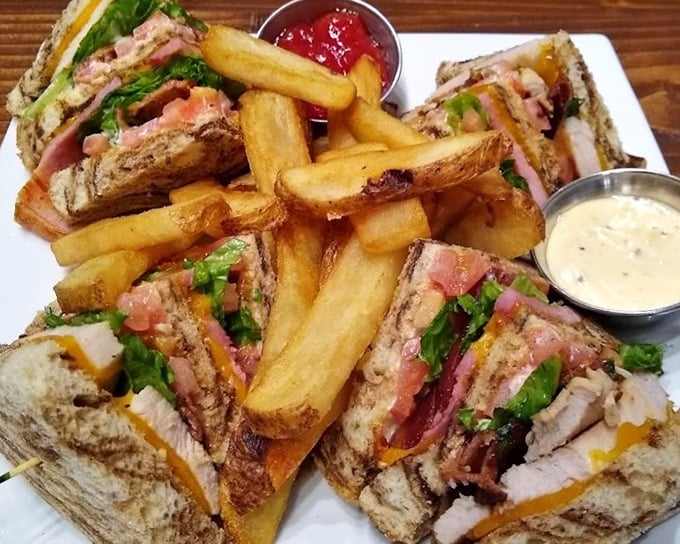 The club sandwich, reinvented as an architectural marvel. Layers of meat, cheese, and veggies between toasted bread, with fries standing guard.