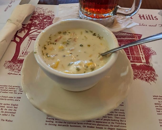 A bowl of what appears to be corn and crab bisque that doesn't just warm your stomach—it hugs your soul with each creamy, seafood-studded spoonful.