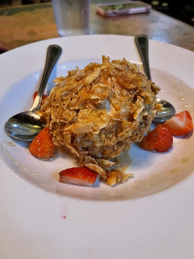 Fried ice cream wearing a crispy cornflake jacket. Those strawberries aren't just garnish&mdash;they're little red witnesses to dessert greatness.