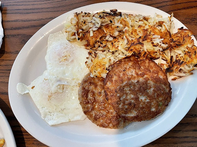 The breakfast trinity: perfectly fried eggs, hash browns with that ideal crispy edge, and a sausage patty that means business. Morning salvation on a plate.