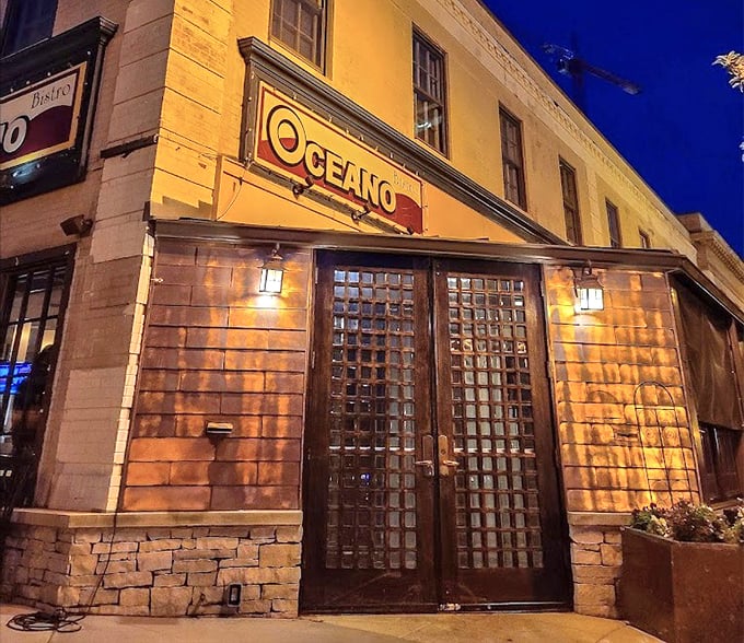 As night falls, Oceano's entrance glows with warm light, a siren call to seafood lovers wandering the streets of Clayton.