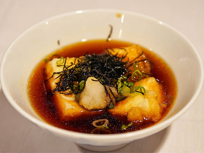 Agedashi tofu swimming in delicate dashi broth&mdash;crispy exterior giving way to silken interior, topped with bonito flakes dancing in the steam.