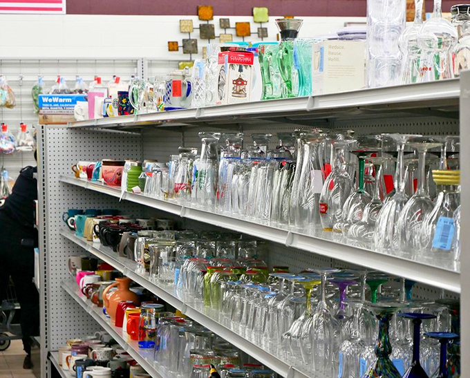 The glassware graveyard sparkles under fluorescent lights. Mismatched crystal and everyday tumblers wait patiently for their chance at a second home.