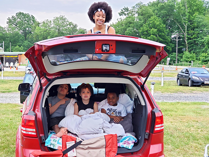 The ultimate drive-in setup: SUV tailgate transformed into a cozy nest. These kids have mastered the art of movie-watching comfort that adults can only envy.