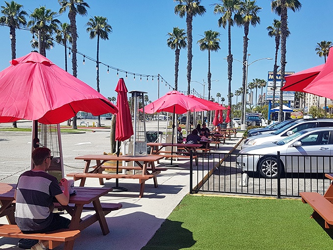 Palm trees stand guard over red umbrellas and picnic tables, creating California's version of the perfect outdoor dining room.