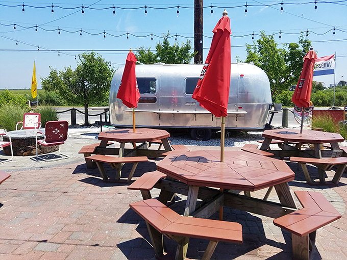 Octagonal picnic tables under bright red umbrellas create the perfect setting for cracking crabs and making memories. The Airstream gleams like a silver beacon of summer.