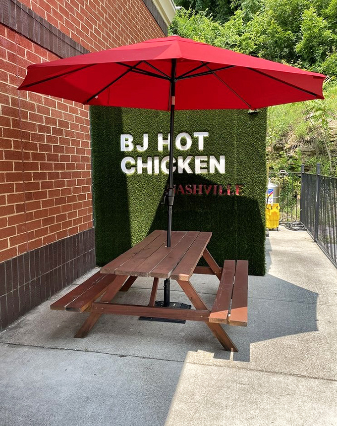 Outdoor seating with a touch of green &ndash; the perfect spot to enjoy Nashville's signature dish while soaking up some Tennessee sunshine. That red umbrella matches the heat level.