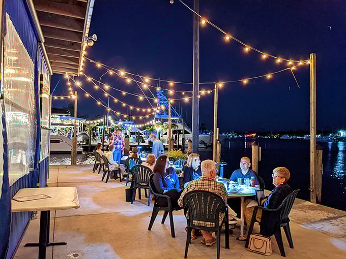 String lights transform the dock into an enchanted evening spot. The water reflects both the lights and your good decision to dine here.