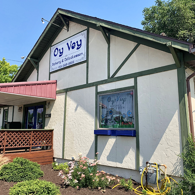 Summer sunshine highlights the charming cottage-like exterior. The blue-trimmed window and neat landscaping make this culinary destination instantly inviting.