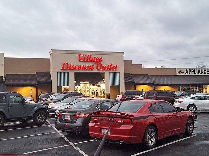 Even at dusk, Village Discount Outlet's glow draws in the deal-seekers. The parking lot fills with cars whose owners understand true value.