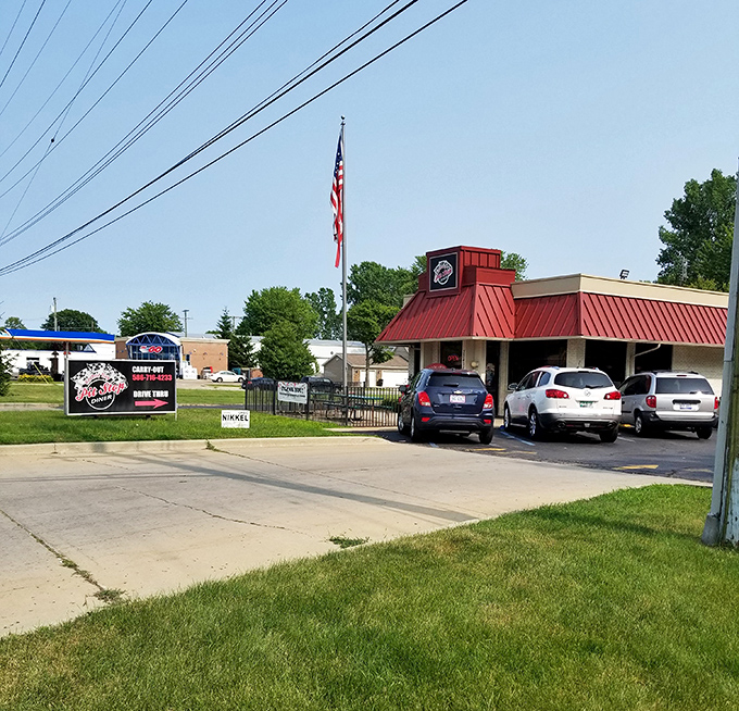 An American flag waves proudly above this roadside haven, where cars in the parking lot tell the story of a community gathering place.
