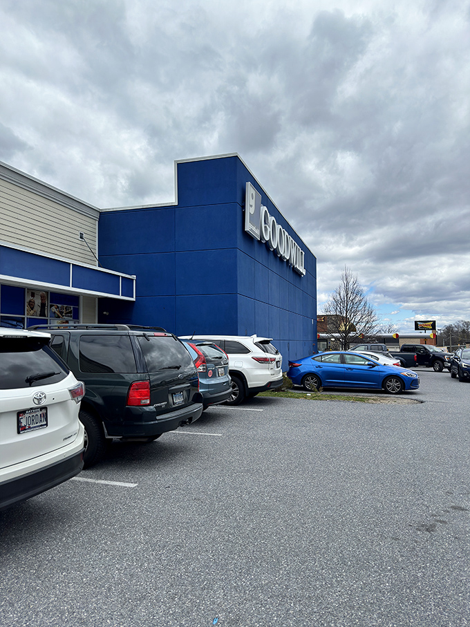 The blue beacon of bargains under moody Maryland skies – Goodwill's parking lot, where treasure hunters begin their quests.